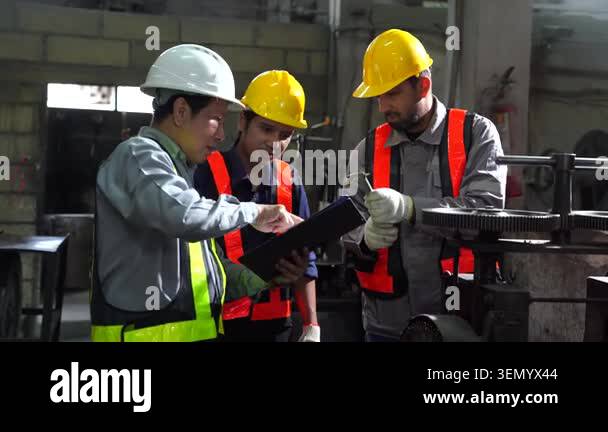 Professional engineers and factory workers inspecting and operating ...