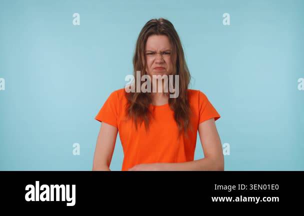 A young woman, wearing an orange shirt, crosses her arms and displays a ...
