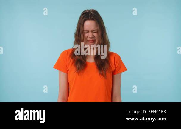 A woman in an orange shirt displaying a strong expression of disgust ...
