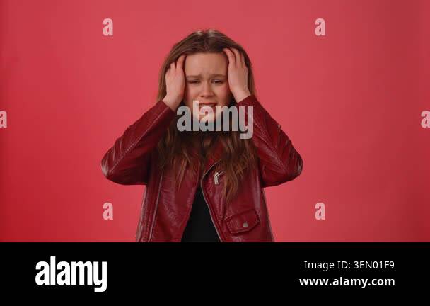 A woman showing frustration, hands on head, eyes closed, against a ...