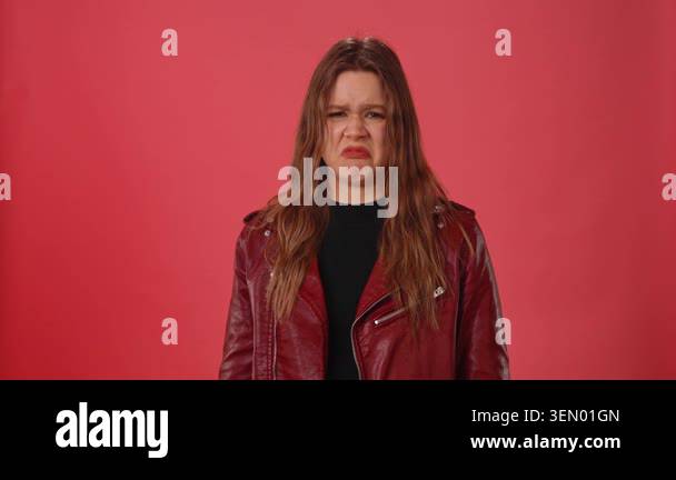 A young woman showing a disgusted expression while standing against a ...