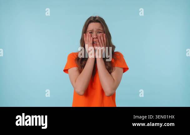 A young woman in an orange shirt shows stress and frustration. Her ...
