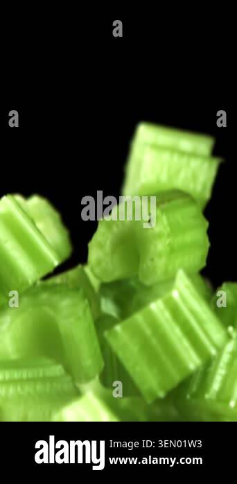Sliced pieces of celery rise and fall on a black background. Filmed on ...