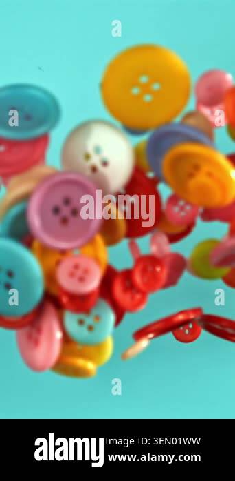 Multi-colored sewing buttons fall on the table. Filmed on a high-speed ...