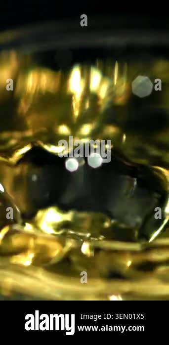 A drop falls into a glass of white wine. Filmed on a high-speed camera ...