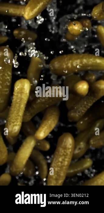 Pickled cucumbers fly and fall on a black background. Filmed on a high ...