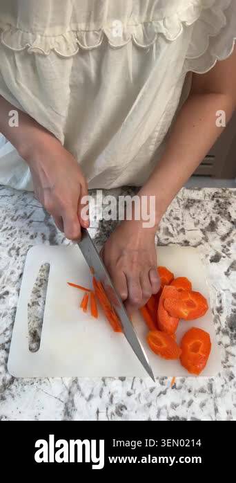 Focused asian female home cook passionately slicing fresh carrot on ...