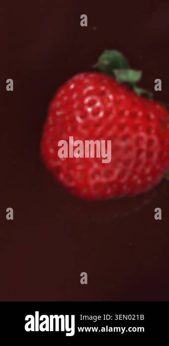Strawberries fall into chocolate. Filmed on a high-speed camera at 1000 ...