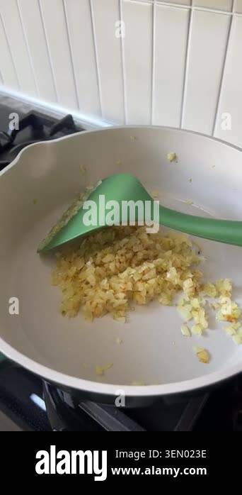 Enthusiastic asian female home cook frying fresh chopped garlic in ...