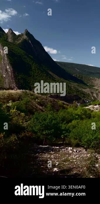 Mountain Valley With Riverbed And Village Under Jagged Peaks, Sunlit ...