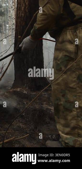 Smoldering Debris Raked By Camouflaged Firefighter, Gloved Hands ...