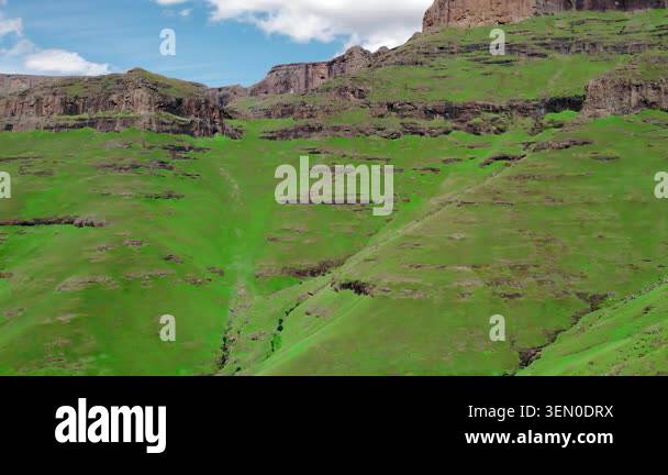 Wide scenic view of a lush green mountainside with rocky cliffs and ...