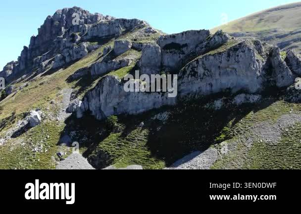 Wide scenic view of rugged rocky cliffs and green grassy mountain ...