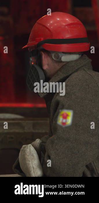 Foundry Worker In Helmet Watching Molten Pour, Protective Mask And ...