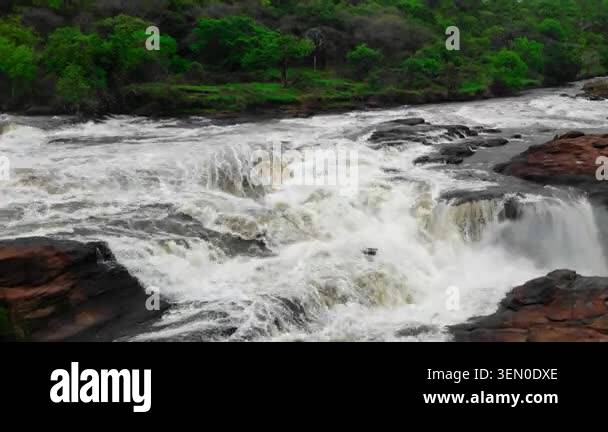 A wide view of a fast-moving waterfall and rapids flowing through dark ...
