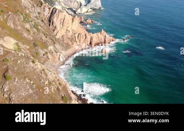 Aerial view of a dramatic rocky coastline with steep cliffs, turquoise ...