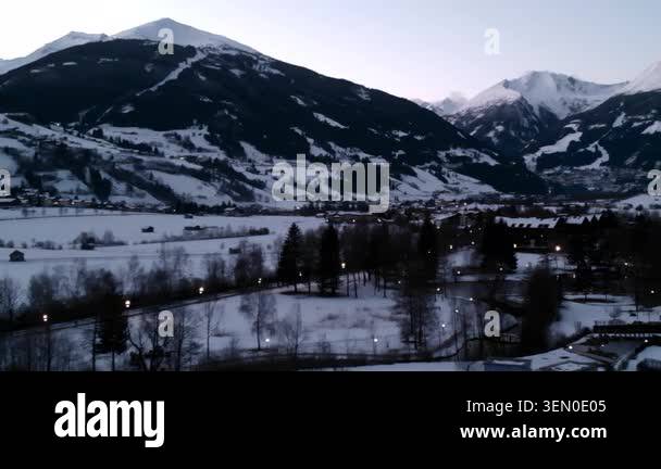 Wide scenic view of snow covered mountain peaks rising above a dark ...