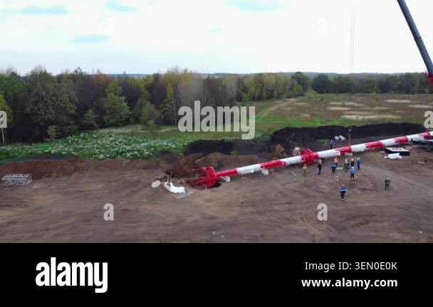 Overhead view of a crane handling a long red and white structure at an ...