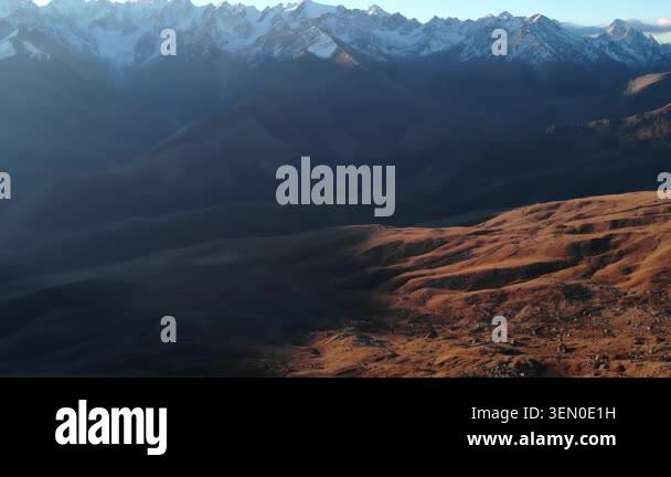 Wide aerial landscape of rugged barren hills and rocky ridges with snow ...
