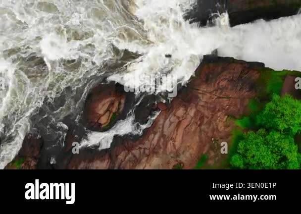 Top-down aerial view of powerful whitewater rushing over dark rocks and ...