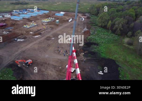 Drone view over a broad earthworks construction site with a tall crane ...