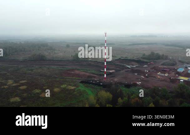 Aerial view of a tall red and white smokestack rising over a foggy ...