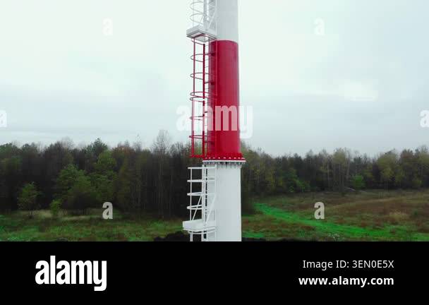 A tall white industrial tower with a red central section and protective ...
