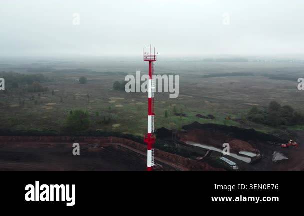 A tall red and white steel tower stands in a flat wetland landscape ...