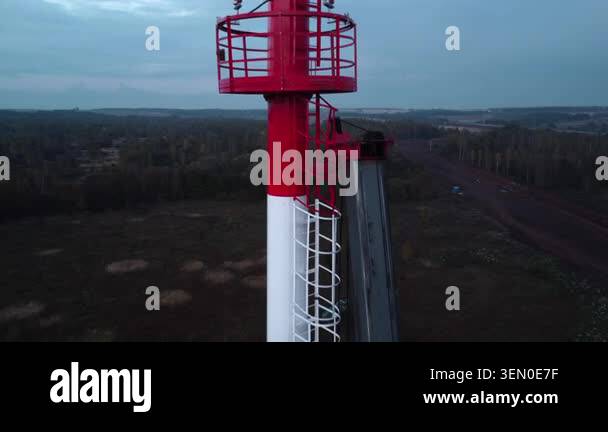 Red and white industrial tower with a circular safety platform and ...