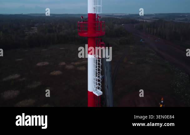 A tall red and white tower with a ladder and platform rises above a ...