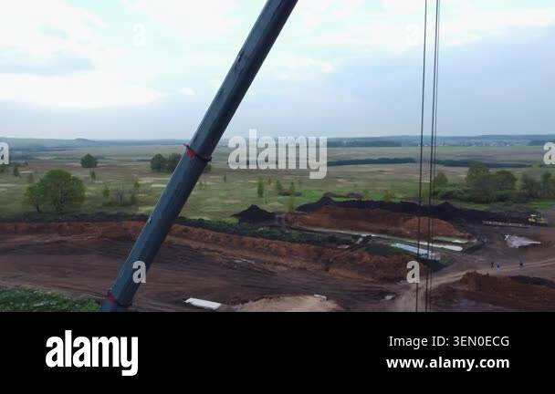 A tall crane boom rises over a large construction area with excavated ...