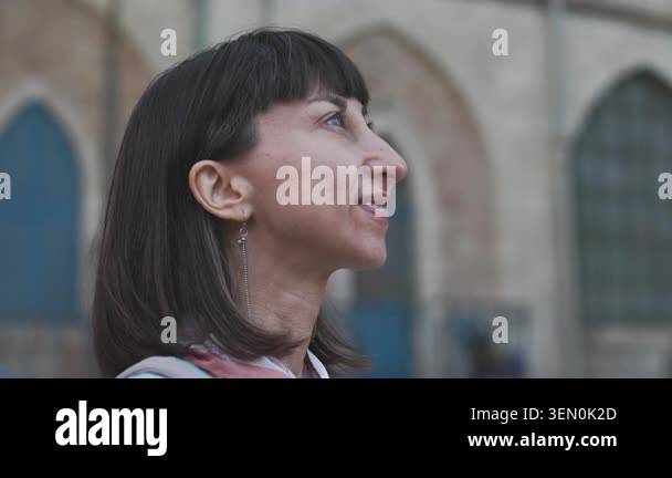 Close-up of a dark-haired woman holding a vintage camera near her face ...