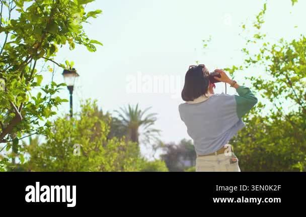 A girl photographs the city with a vintage camera, smiling in the ...