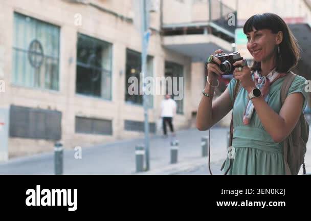 Close-up of a dark-haired woman holding a vintage camera near her face ...