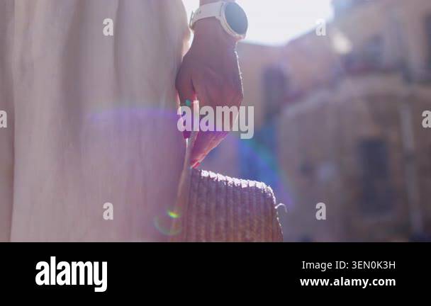 A close-up of a womans hand holding a hat in warm sunlight, against a ...