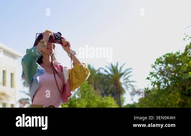 A girl photographs the city with a vintage camera, smiling in the ...