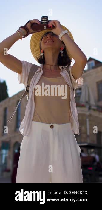 Vertical shot. A young woman in a straw hat and summer dress holds the ...