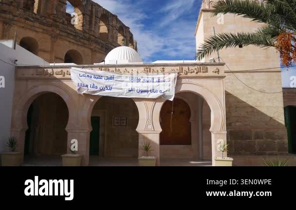 El Jem Amphitheatre and nearby mosque in Tunisia under blue sky ...