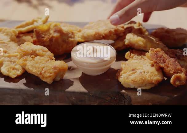 Close-up slow motion footage of a young woman's hand dipping a crispy ...