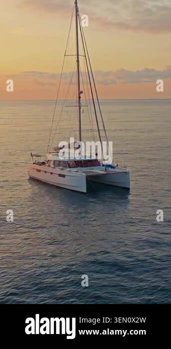 Aerial view of catamaran anchored in the calm sea at amazing sunset ...