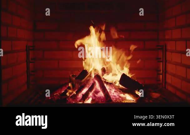 A cozy burning bonfire with bright orange flames and glowing logs ...