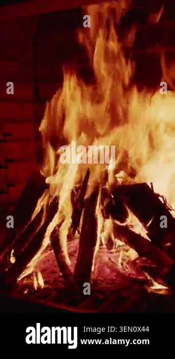 A cozy burning bonfire with bright orange flames and glowing logs ...