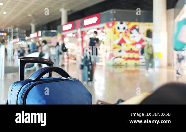 A time-lapse video of a blue travel bag standing still in an airport ...