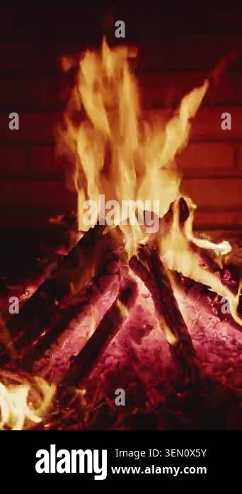 A cozy burning bonfire with bright orange flames and glowing logs ...