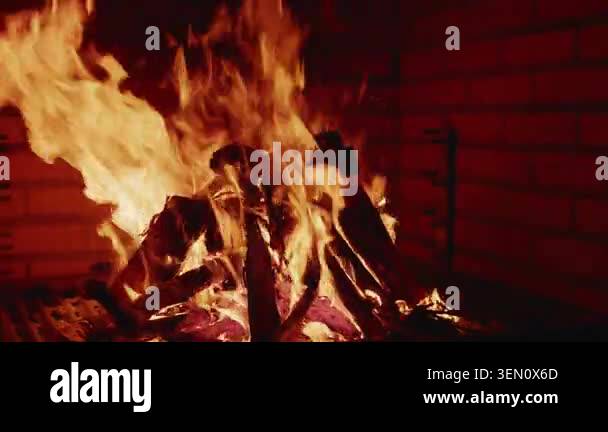 A cozy burning bonfire with bright orange flames and glowing logs ...