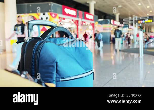 A time-lapse video of a blue travel bag standing still in an airport ...