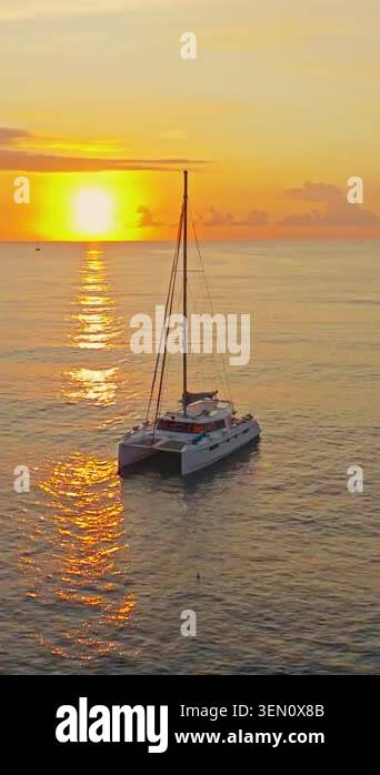 Aerial view of catamaran anchored in the calm sea at amazing sunset ...