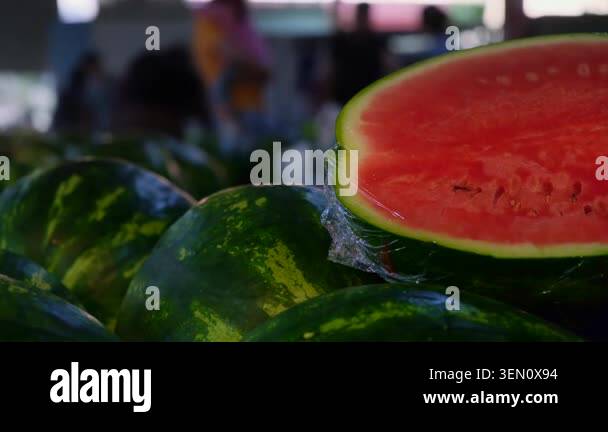 Closeup watermelons on market table, glossy green rinds and halfcut red ...