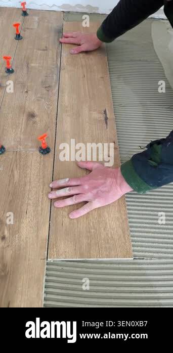 A male construction worker carefully lays and levels a large wood ...