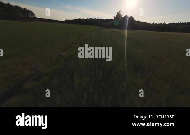 Dynamic FPV drone footage flying low over green agricultural fields ...